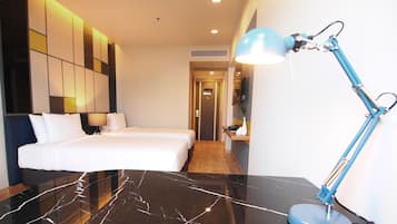 Quarto de hotel com uma cama grande, uma mesa com tampo de mármore e um abajur azul.