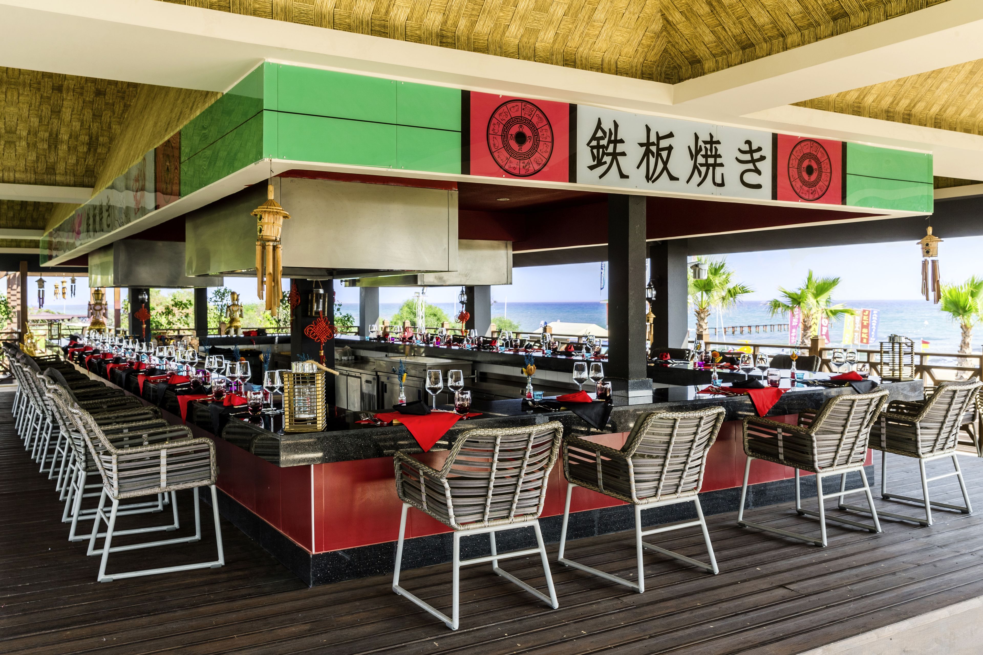 Um restaurante com área de bar, mesas ao ar livre e vista para o mar.