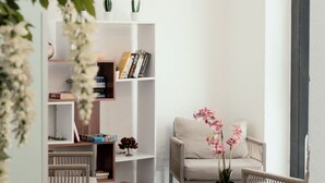 Uma sala de estar moderna com uma estante, um sofá, uma mesa de centro e um vaso com planta.