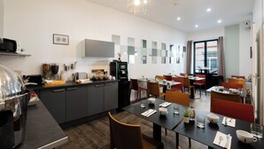 Uma área de refeições moderna em hotel, com buffet, mesas e uma grande janela.