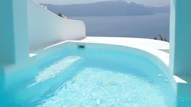 Vista nítida de uma piscina com vista para o mar e montanhas ao longe.
