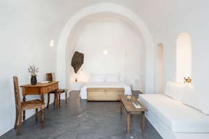 Quarto minimalista com cama, escrivaninha de madeira, cadeira, sofá e mesa de centro.