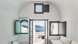 Quarto moderno com vista para o mar, um sofá, uma mesinha e uma TV integrada.