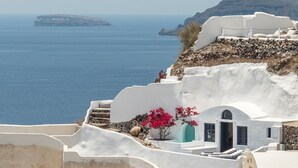 Um edifício de paredes brancas com vista para o mar e uma ilha ao longe.