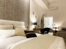 Quarto de hotel com uma cama grande, uma escrivaninha, uma cadeira e um guarda-roupa.