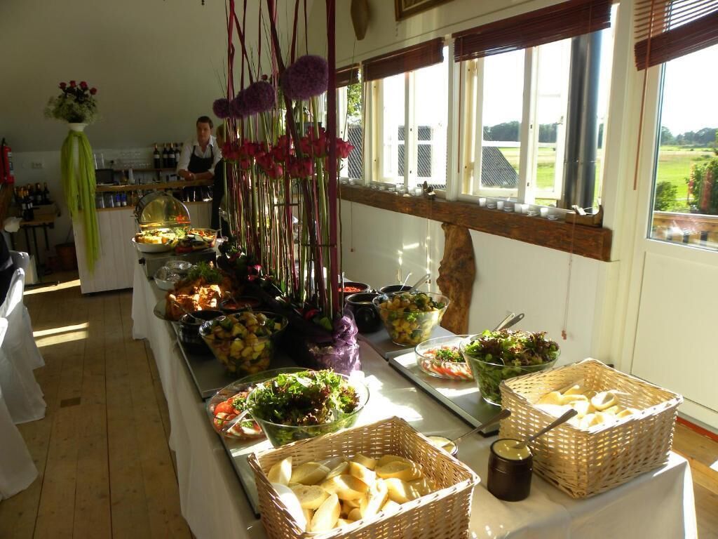 Mesa de buffet com diversos alimentos e uma pessoa servindo.