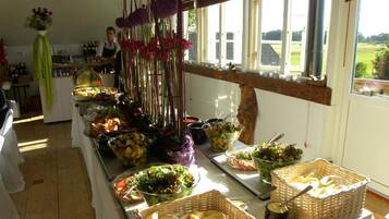 Mesa de buffet com diversos alimentos e uma pessoa servindo.