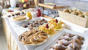 Um buffet de café da manhã com pães, frutas e bebidas.