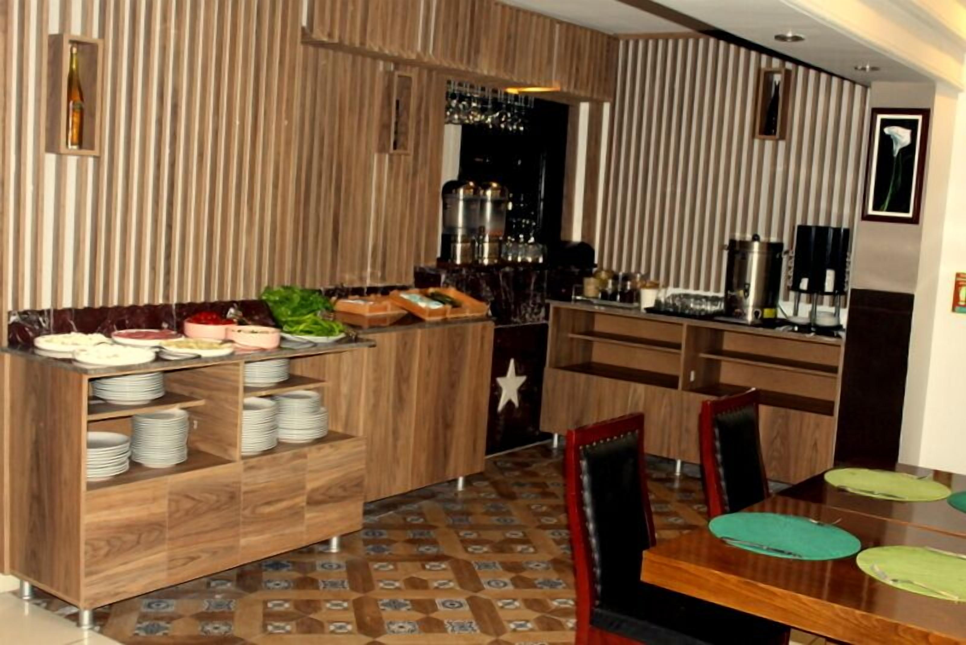 Uma área de refeições moderna com um balcão de buffet de madeira, um bar e um piso estampado.