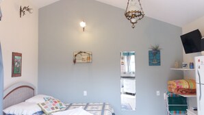 Quarto com cama, cómoda, televisão e janela.