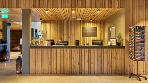 Uma receção com design em painel de madeira, um computador Lenovo, um sinal a indicar o Restaurante Drangar e um aviso de proibido fumar.