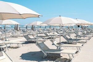 Uma praia privada, espreguiçadeiras, guarda-sóis de praia