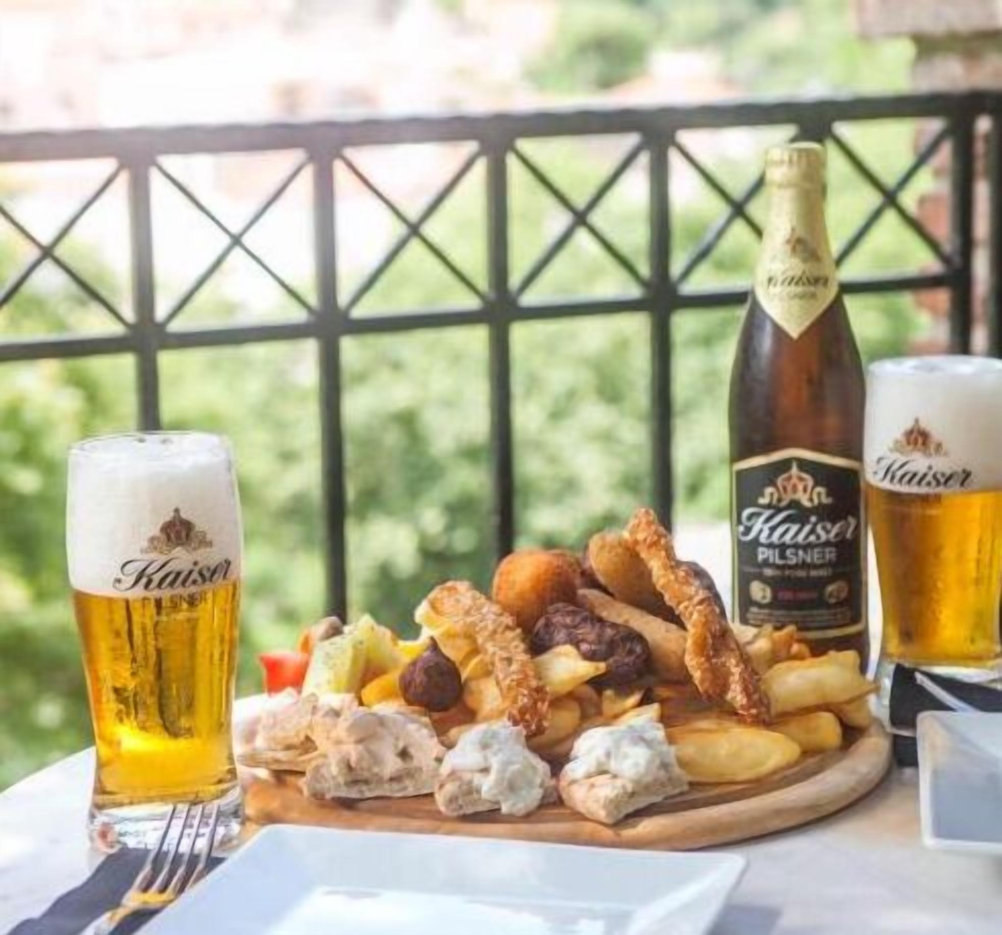 Uma mesa com um prato de comida, duas canecas de cerveja e uma garrafa de cerveja.