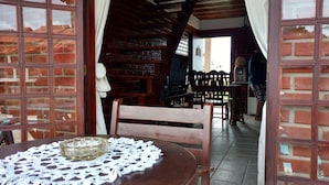Uma área de refeições acolhedora com uma mesa de madeira, toalha rendada e cinzeiro de vidro.