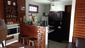 Uma cozinha com parede de tijolos, máquina de café, liquidificador e geladeira.