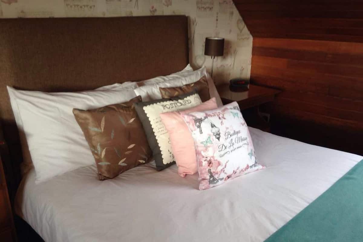 Cama com roupa branca, várias almofadas e manta azul-turquesa.