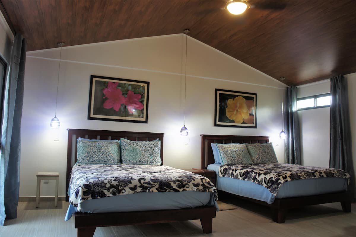 Quarto com duas camas, cabeceiras de madeira e arte floral nas paredes.