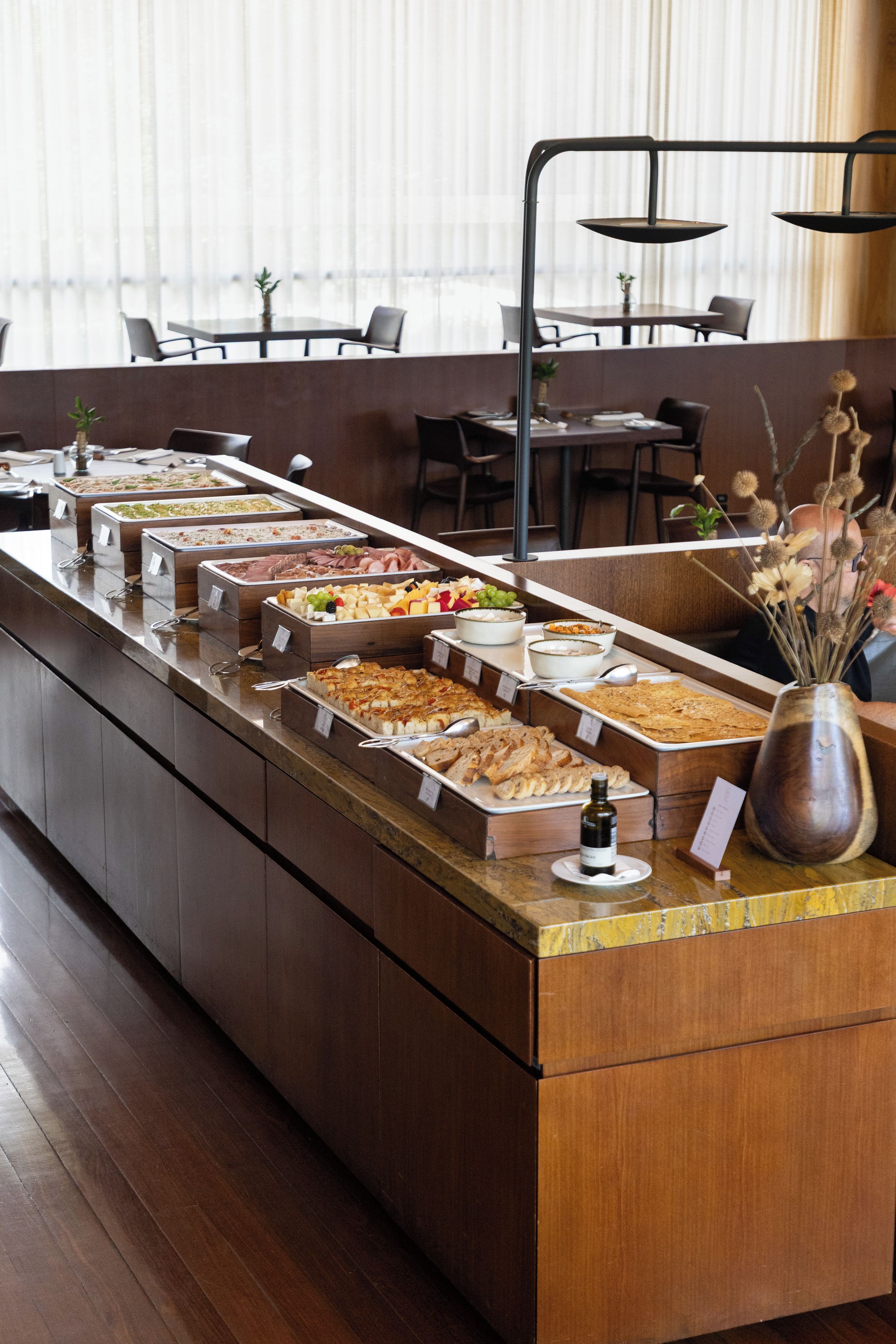 Uma área de buffet com diversas opções de comida e um vaso com flores secas.