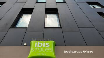 Um edifício alto com uma placa indicando 'ibis Styles Hotels Bucharest Erbas'.