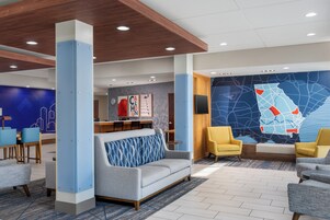 Um lobby moderno com um sofá, cadeiras, um mural de mapa e um balcão de recepção.
