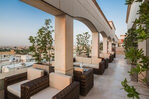 Terraço no telhado com área de estar ao ar livre, colunas e plantas em vasos.