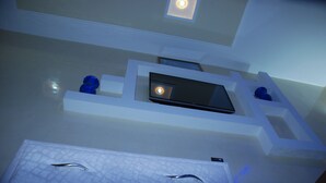 Uma casa de banho moderna com toucador branco, espelho e luz embutida no teto.
