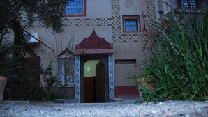 Um edifício com estilo arquitetônico tradicional, destacando uma porta em arco central e molduras decorativas nas janelas.
