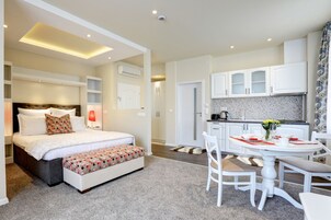 Suíte júnior, 1 cama Queen, cozinha americana, no canto | Área de estar | TV de tela plana 43 polegadas com canais via satélite, TV, livros