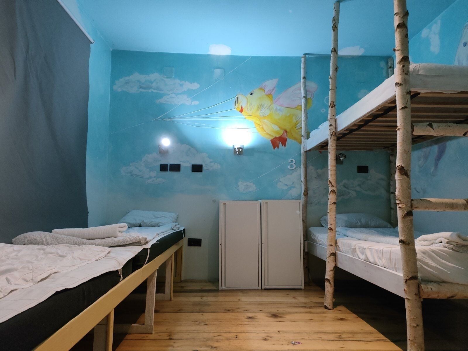 Quarto com beliches, um guarda-roupa e um mural na parede com um pássaro amarelo.