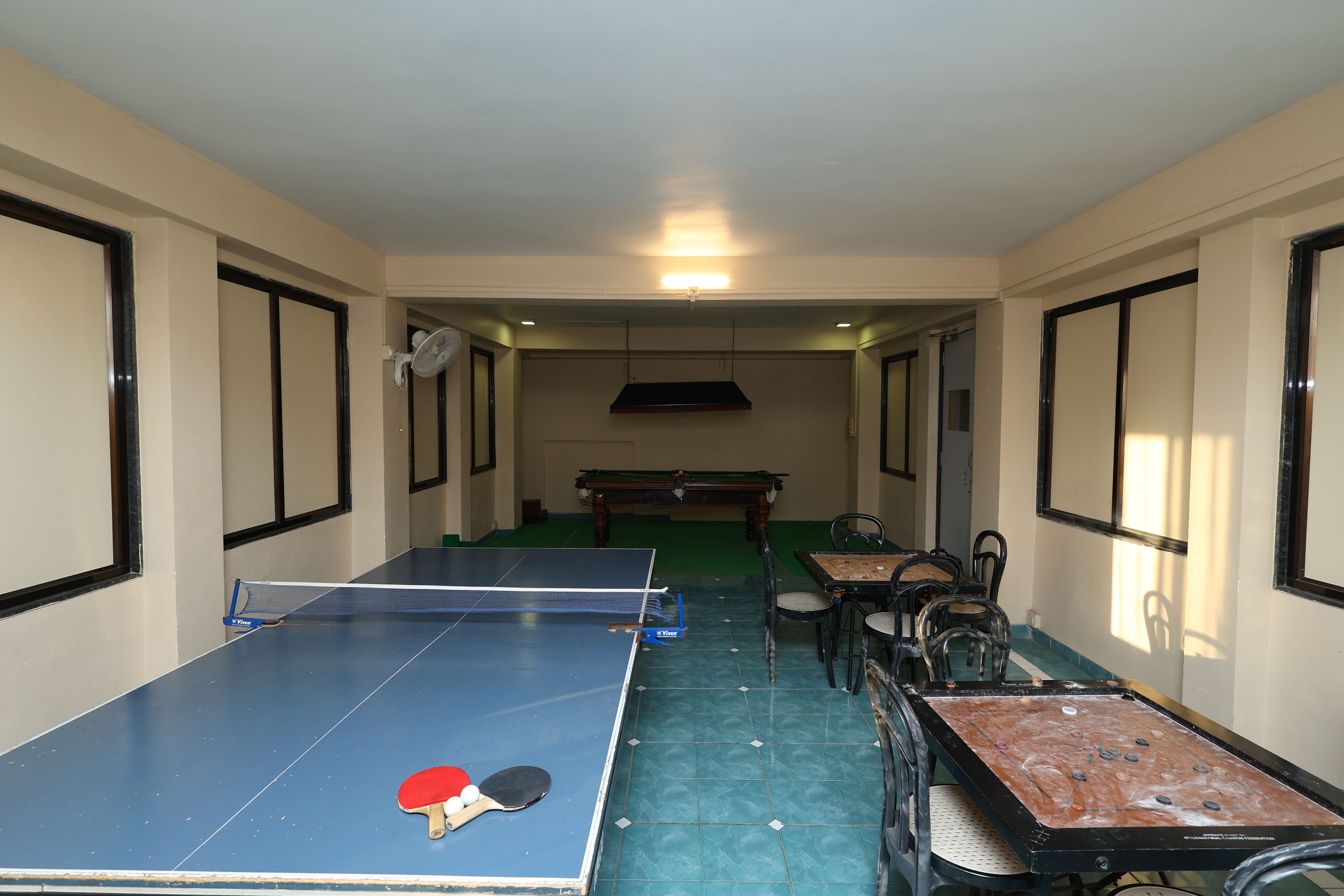 Quarto com mesa de pingue-pongue, mesa de bilhar e várias cadeiras.