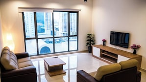Uma sala de estar moderna com um sofá, uma mesa de centro, uma televisão e uma janela grande com vista para a cidade.