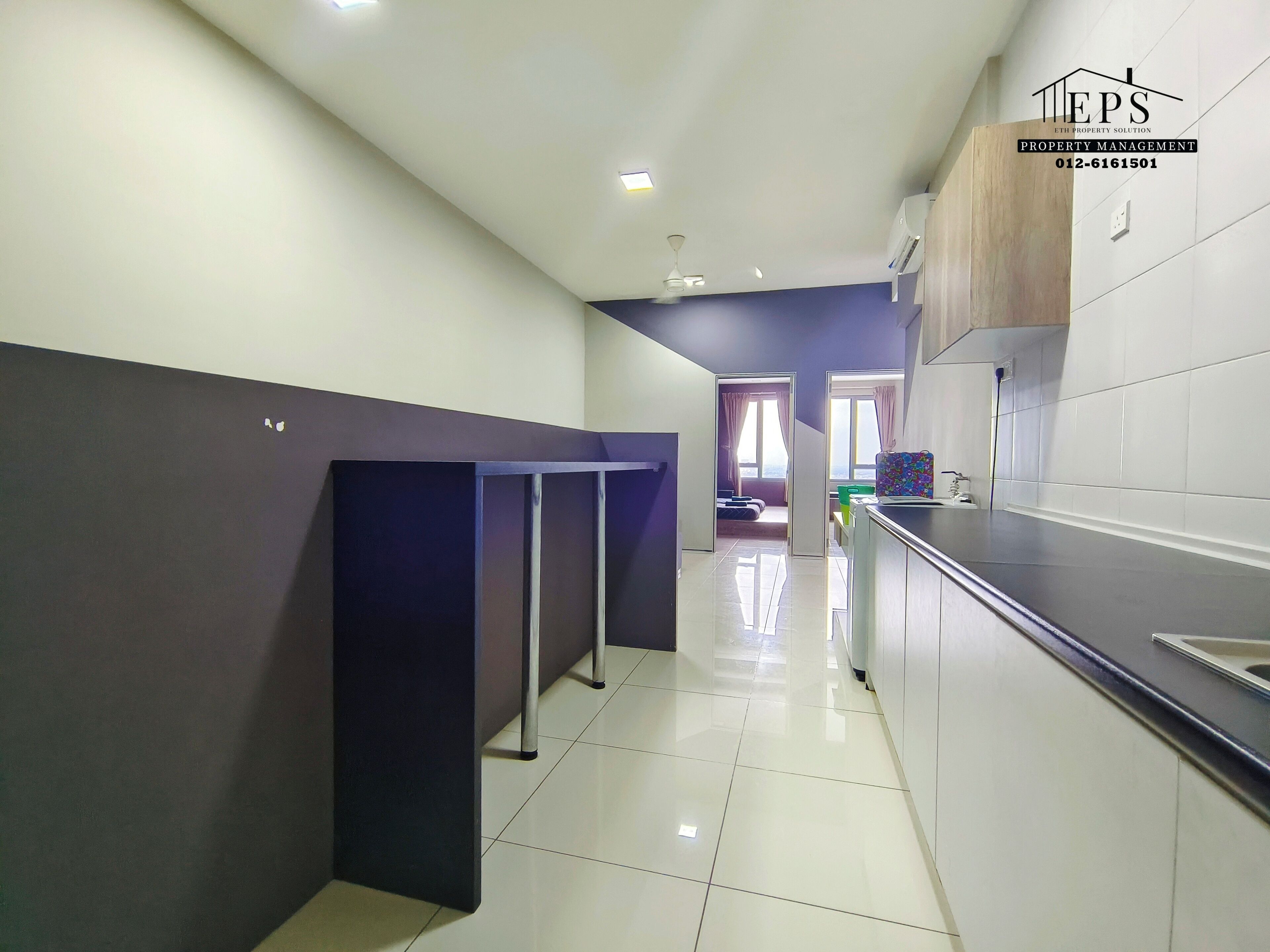 Cozinha moderna com bancada escura, piso de azulejos brancos e vista para um quarto com cama e cortinas.
