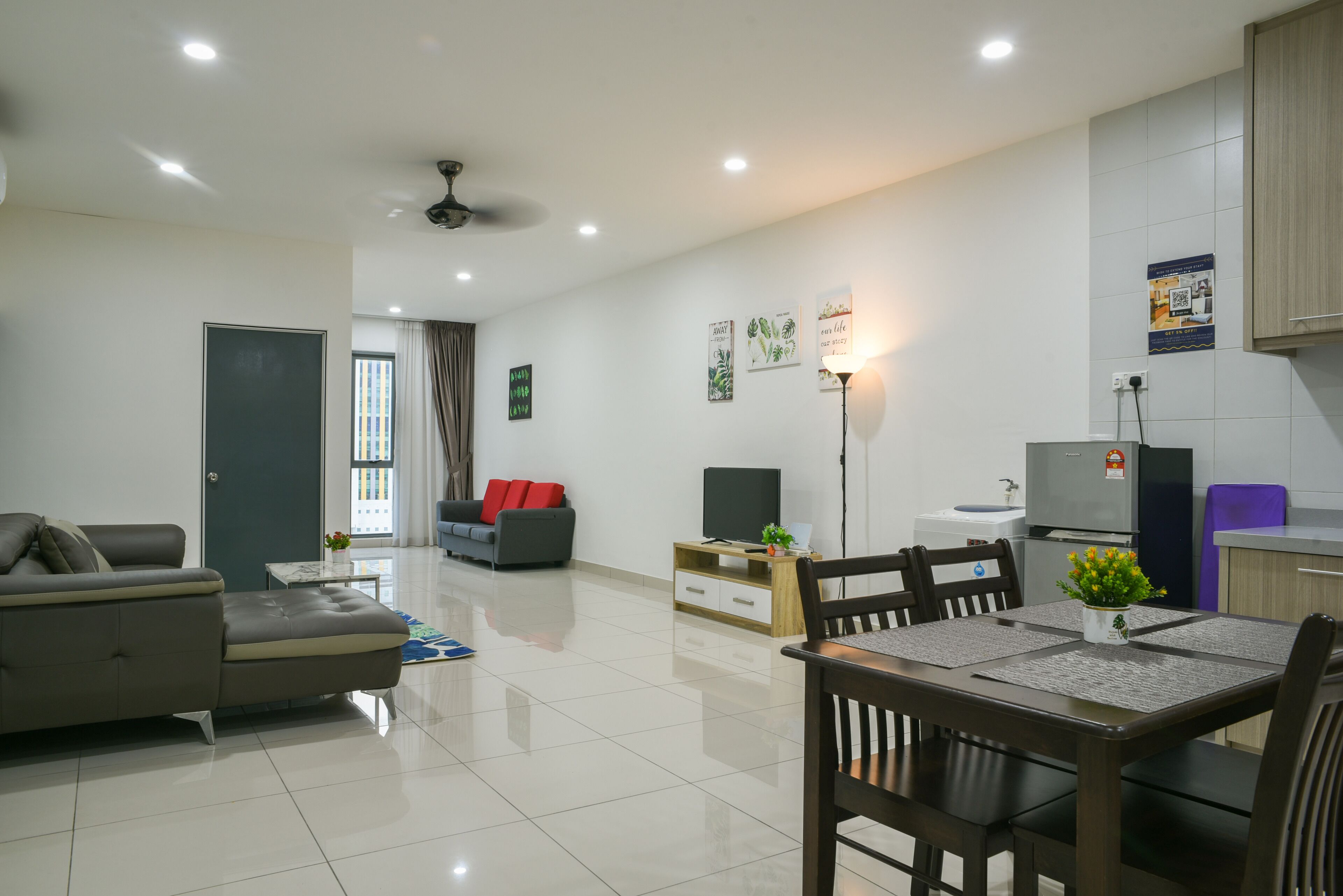 Uma sala de estar moderna com sofá, TV, mesa de jantar e área de cozinha.