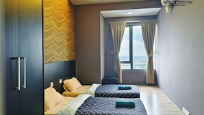 Quarto moderno com duas camas, um guarda-roupa espaçoso, vista pela janela e um candeeiro no teto.