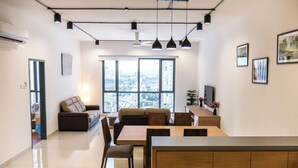 Uma sala de estar moderna com sofá, mesa de jantar e cadeiras. Há uma janela grande com vista para a cidade.