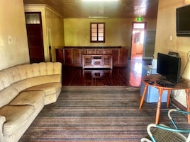 Uma sala de estar com sofá, televisão e uma mesa pequena com controle remoto.