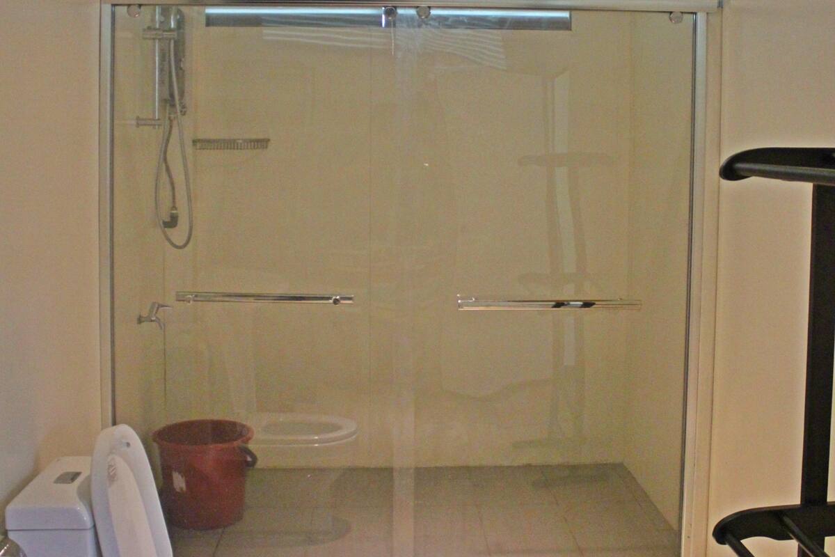 Casa de banho com cabine de duche em vidro, sanita e lavatório.