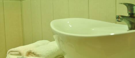 Uma casa de banho com uma sanita branca, uma toalha e um dispensador de sabonete.