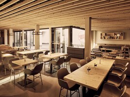 Uma sala de jantar moderna com mesas e cadeiras de madeira, janelas amplas e vista para a cidade.