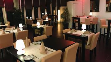 Um restaurante moderno com mesas e cadeiras dispostas num espaço amplo.