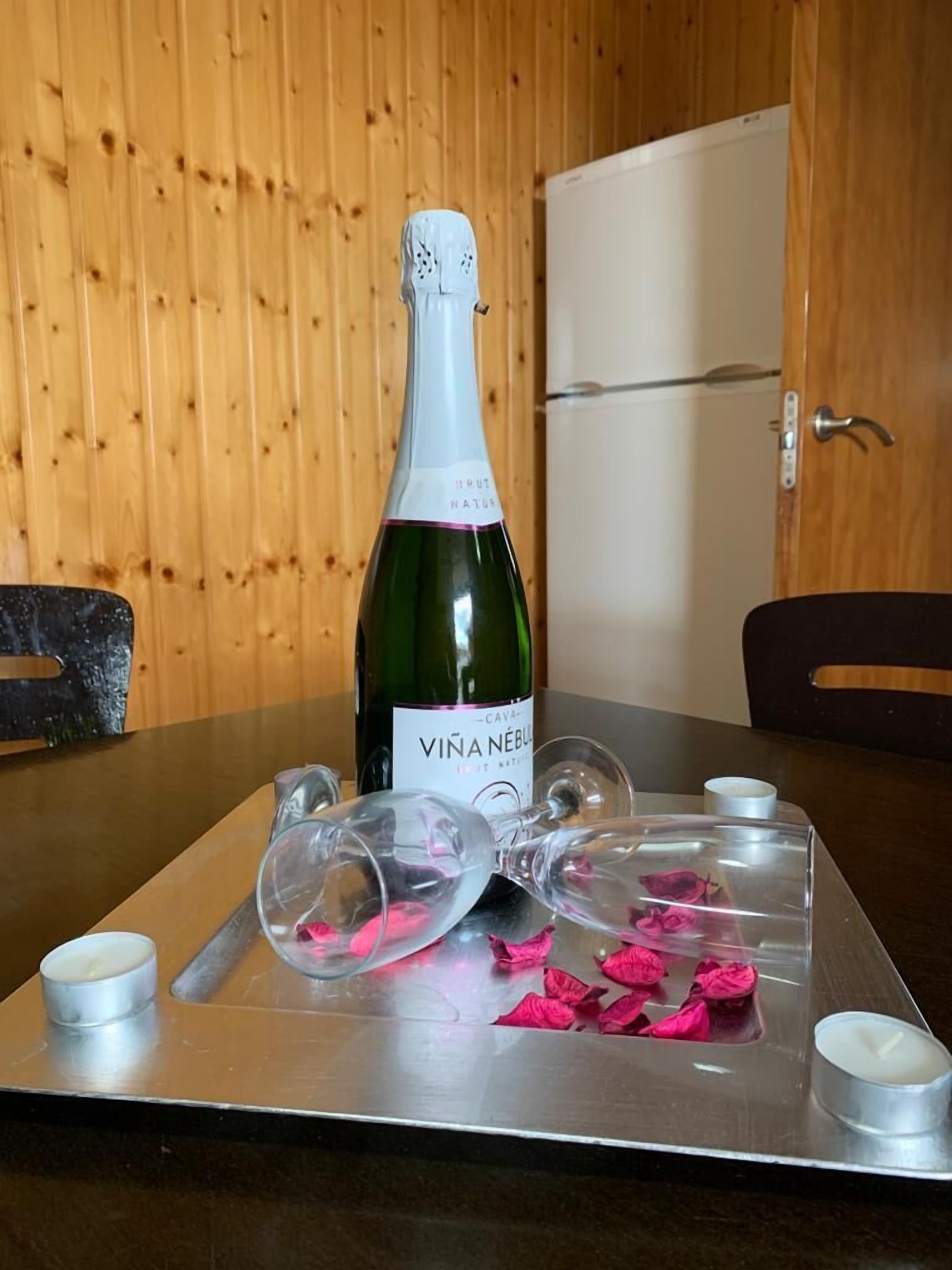 Uma garrafa de vinho Vina Neve sobre uma bandeja com copos e pétalas de rosa.