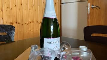 Uma garrafa de vinho Vina Neve sobre uma bandeja com copos e pétalas de rosa.