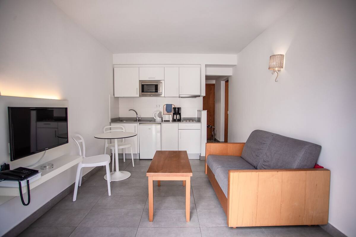 Um espaço compacto com cozinha compacta, área de refeições, sofá e televisão.