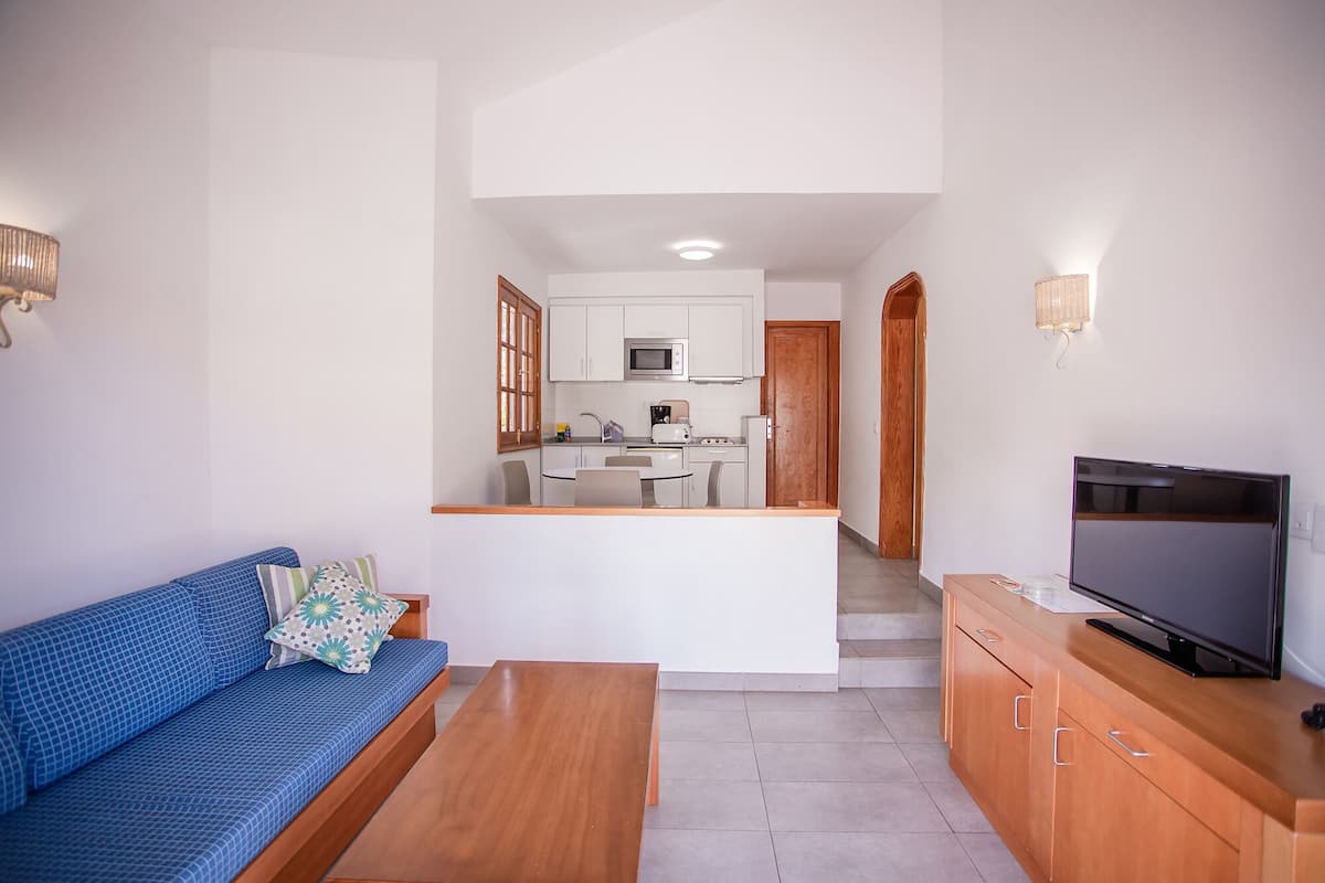 Um espaço compacto com cozinha compacta, um sofá, uma mesa de centro e uma televisão.
