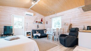 Interior acolhedor de uma cabana com cama, sofá, mesa de jantar e cadeiras.