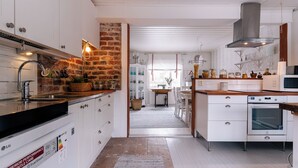 Cozinha moderna com armários brancos, parede de tijolos e uma ilha central.