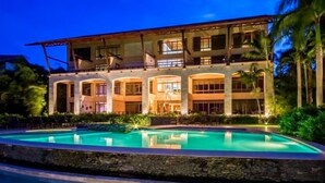 Um edifício de dois andares com uma piscina em frente.