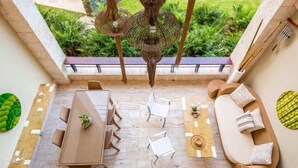 Varanda espaçosa com área de refeições, assentos e vista para um jardim exuberante.