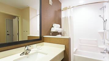Um banheiro de hotel com pia, espelho, porta-toalhas e banheira.