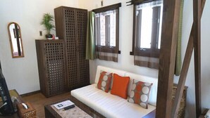 Uma sala de estar acolhedora, com um sofá, uma mesa de centro, um espelho e um aparador de madeira.